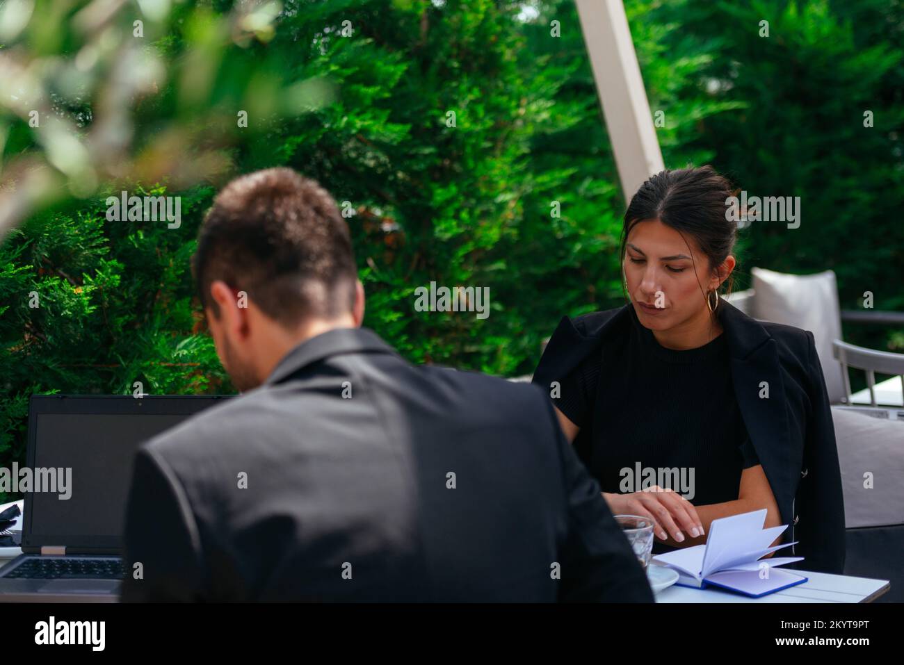 A businessman is working on his phone while his female partner is ...