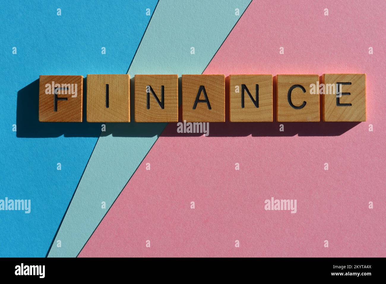 Finance, word in wooden alphabet letters isolated on pink and blue ...