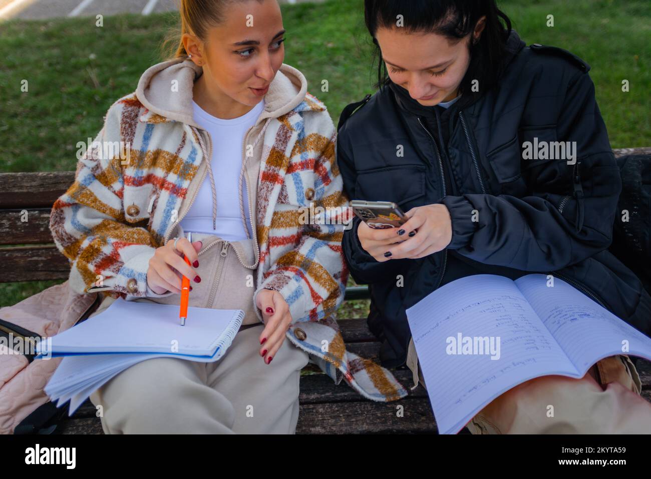 A blonde high school girl is talking to her friend while she is ...