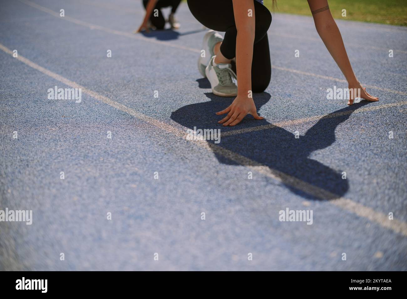 Female sportsperson is about to run on a blue sports track with her ...