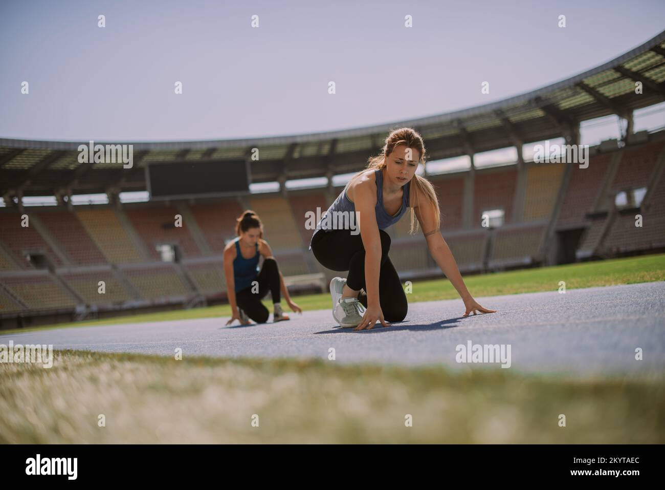 A gorgeous sporty girls are positioning at the start line on the sports ...