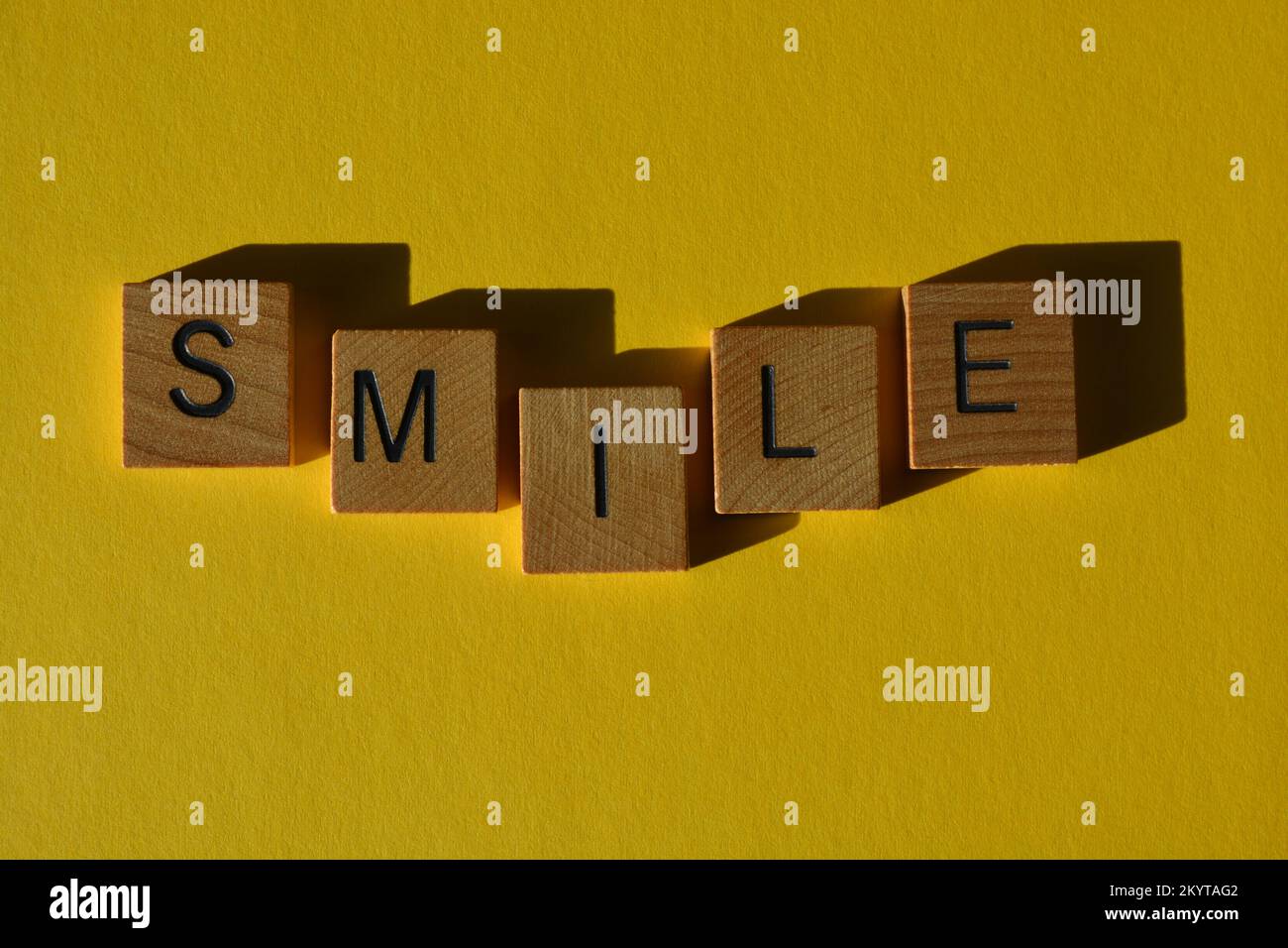Smile, word in wooden alphabet letters isolated on bright yellow ...