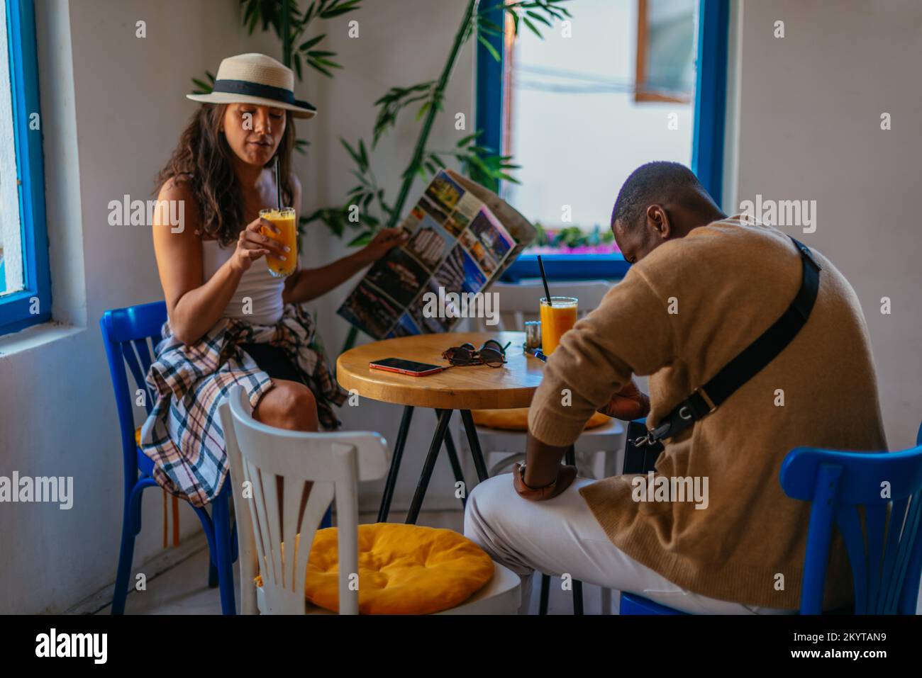 A pretty woman is about to taste her juice. Her boyfriend is looking at ...