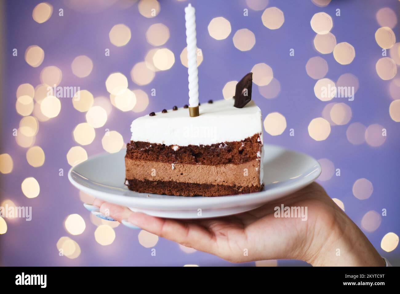 woman holding piece of cake with a candle Stock Photo - Alamy