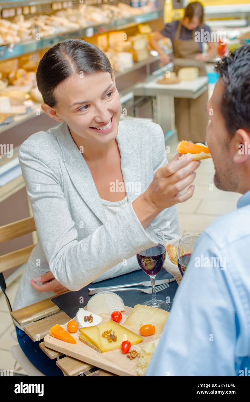 Couple having meal, lady feeding cheese to man Stock Photo - Alamy