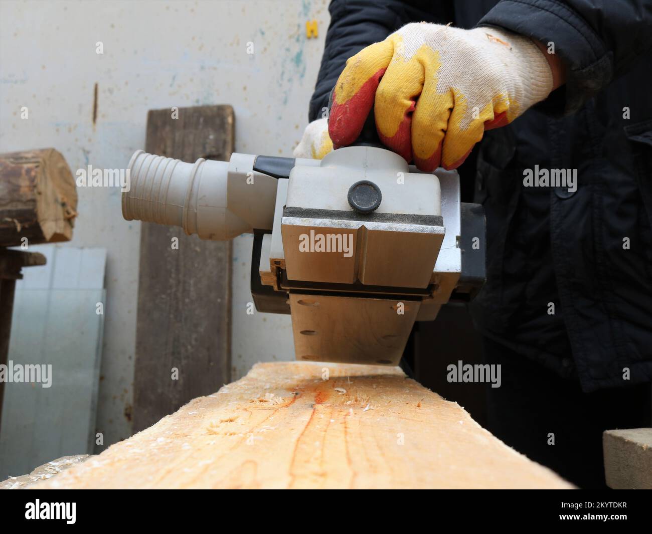 working with an electric planer on a solid wooden board to smooth and ...