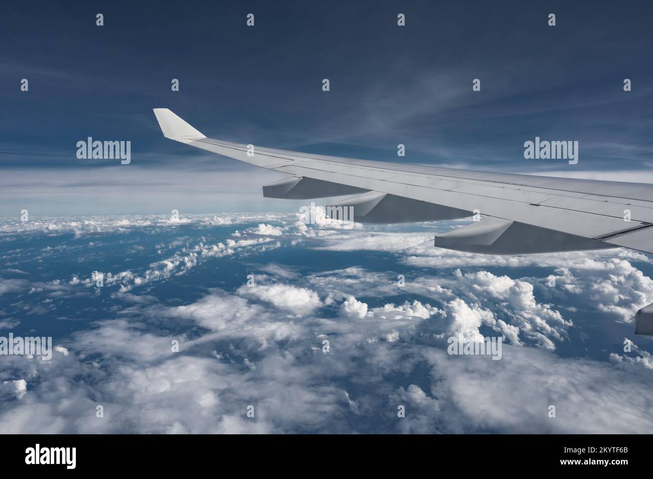 Wing of airplane above flat fluffy clouds surface with soft evening ...
