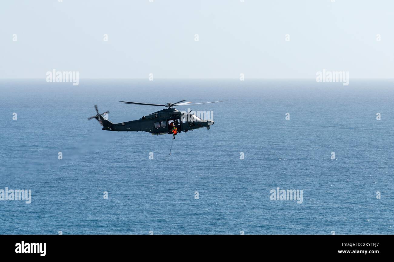 Helicopter flying over open sea while a man is roping down Stock Photo ...