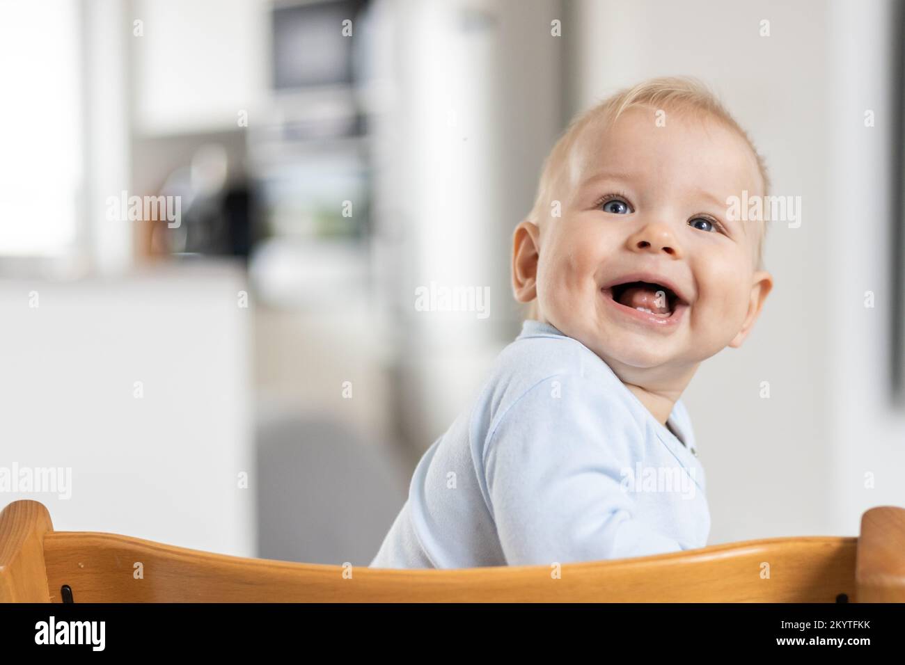 Happy infant sitting in traditional scandinavian designer wooden high ...