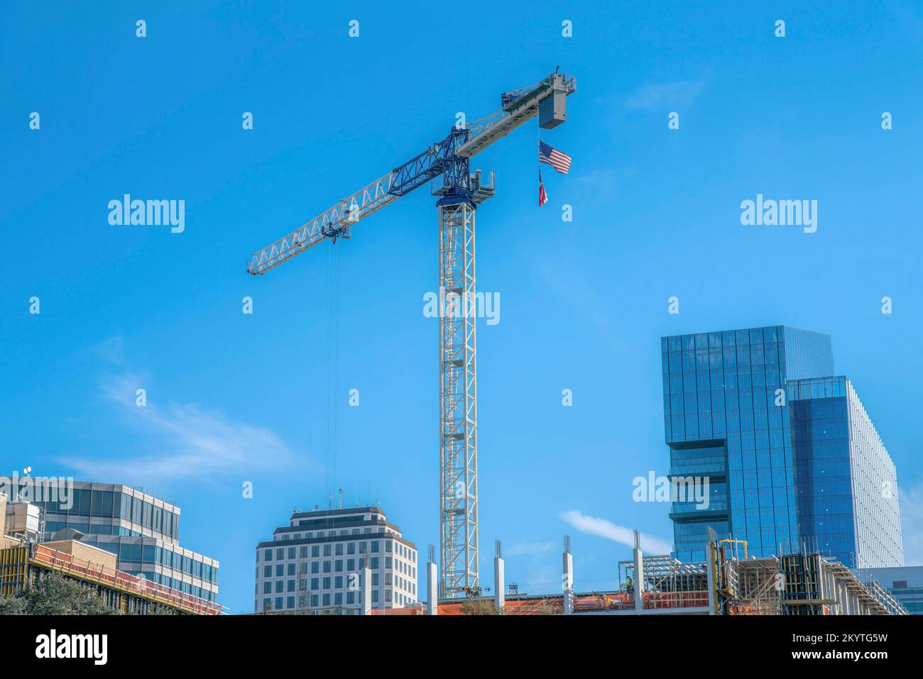 Austin, Texas- Tall tower crane with hanging US flags above the under ...