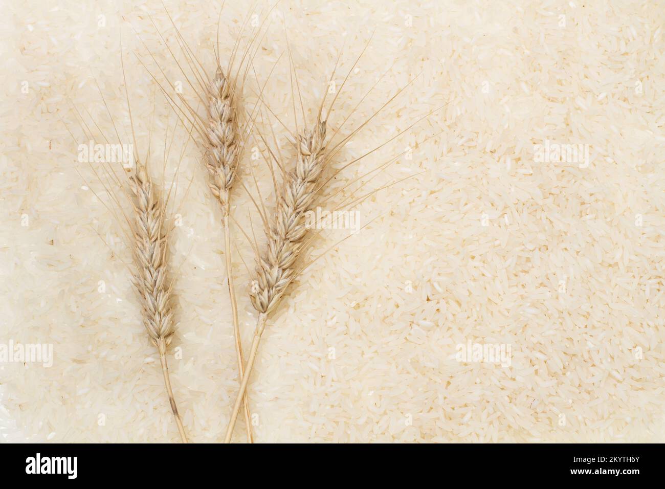 Wheat spikes on a heap of raw rice in a top view Stock Photo - Alamy