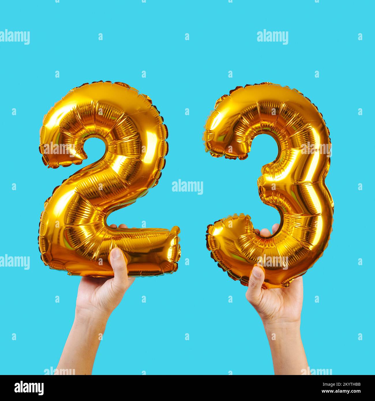 man holds two golden number-shaped balloons forming the number 23 on a ...