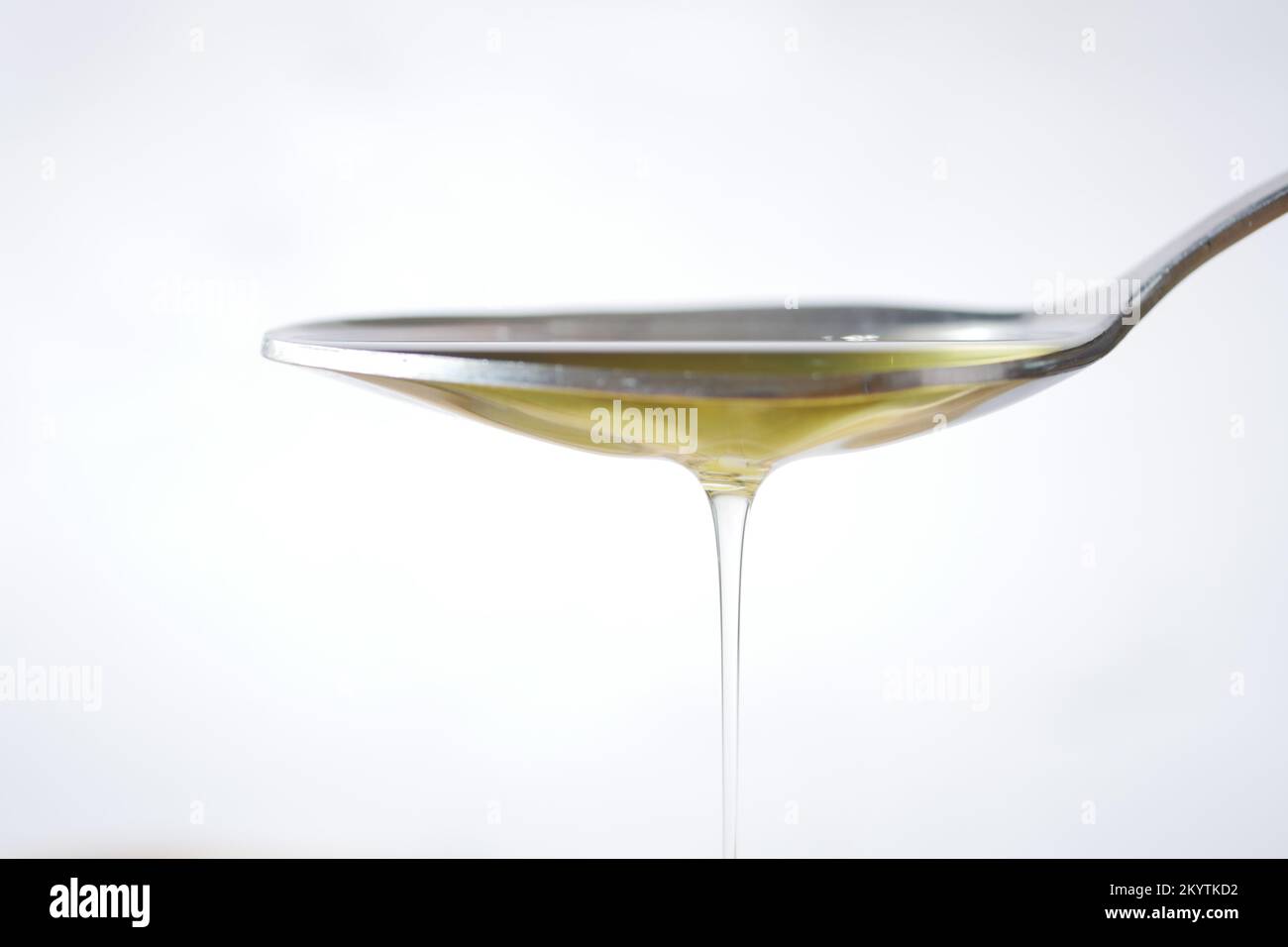 olive oil drop from a silver spoon against white background Stock Photo ...