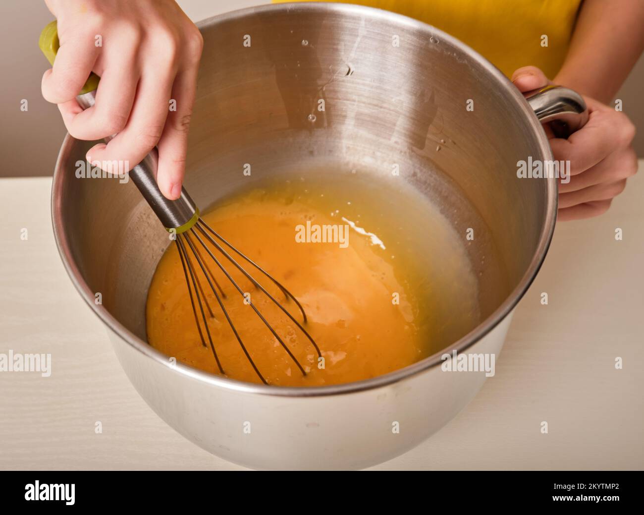 The girl is preparing a homemade cake in the kitchen. Hands beat eggs ...