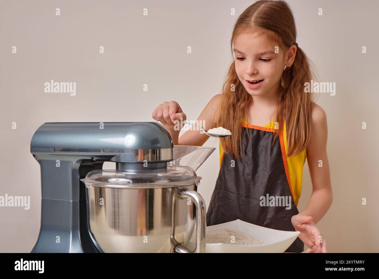 A teenage girl making homemade cake in the kitchen. Mixes the ...