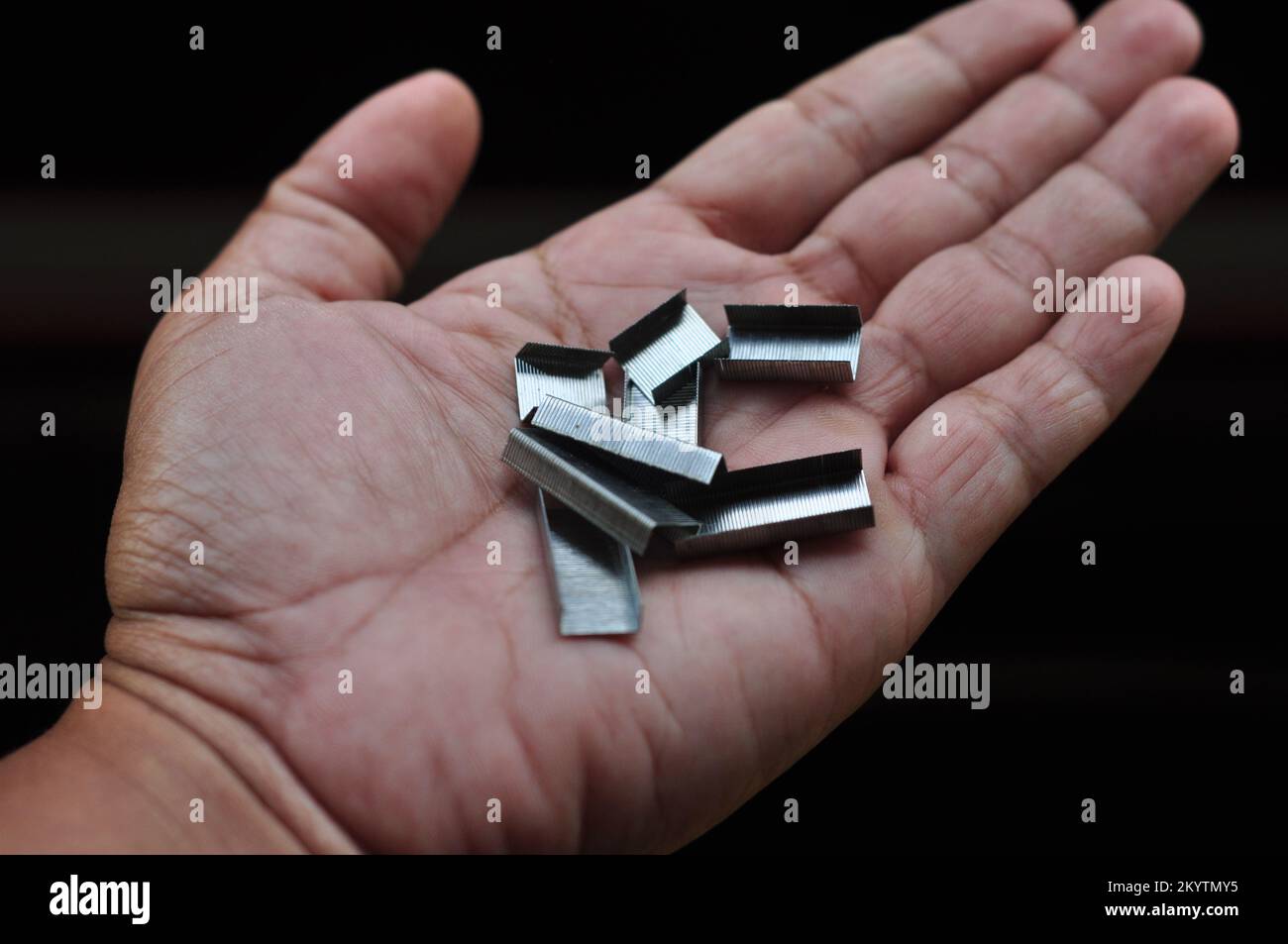 Close-up of male hands holding staples on black background Stock Photo ...