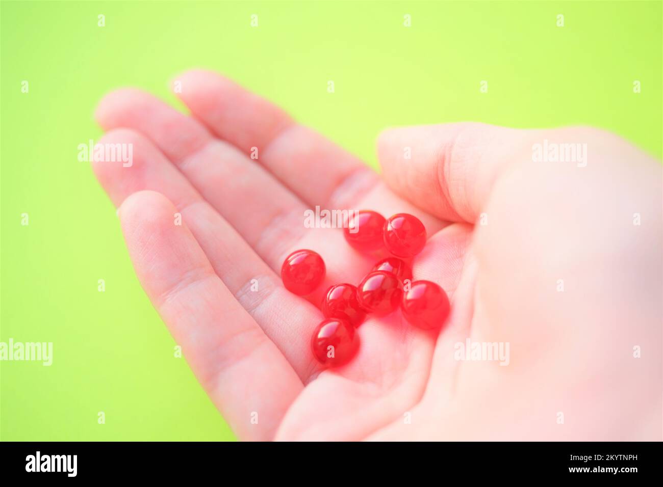 Round red vitamins in human palm. Vivid green background Stock Photo ...