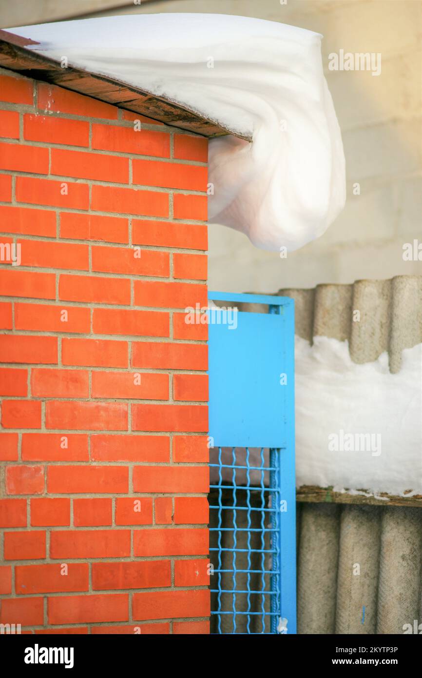 Snowdrift in the form of a wave on the roof of a brick building. Big ...