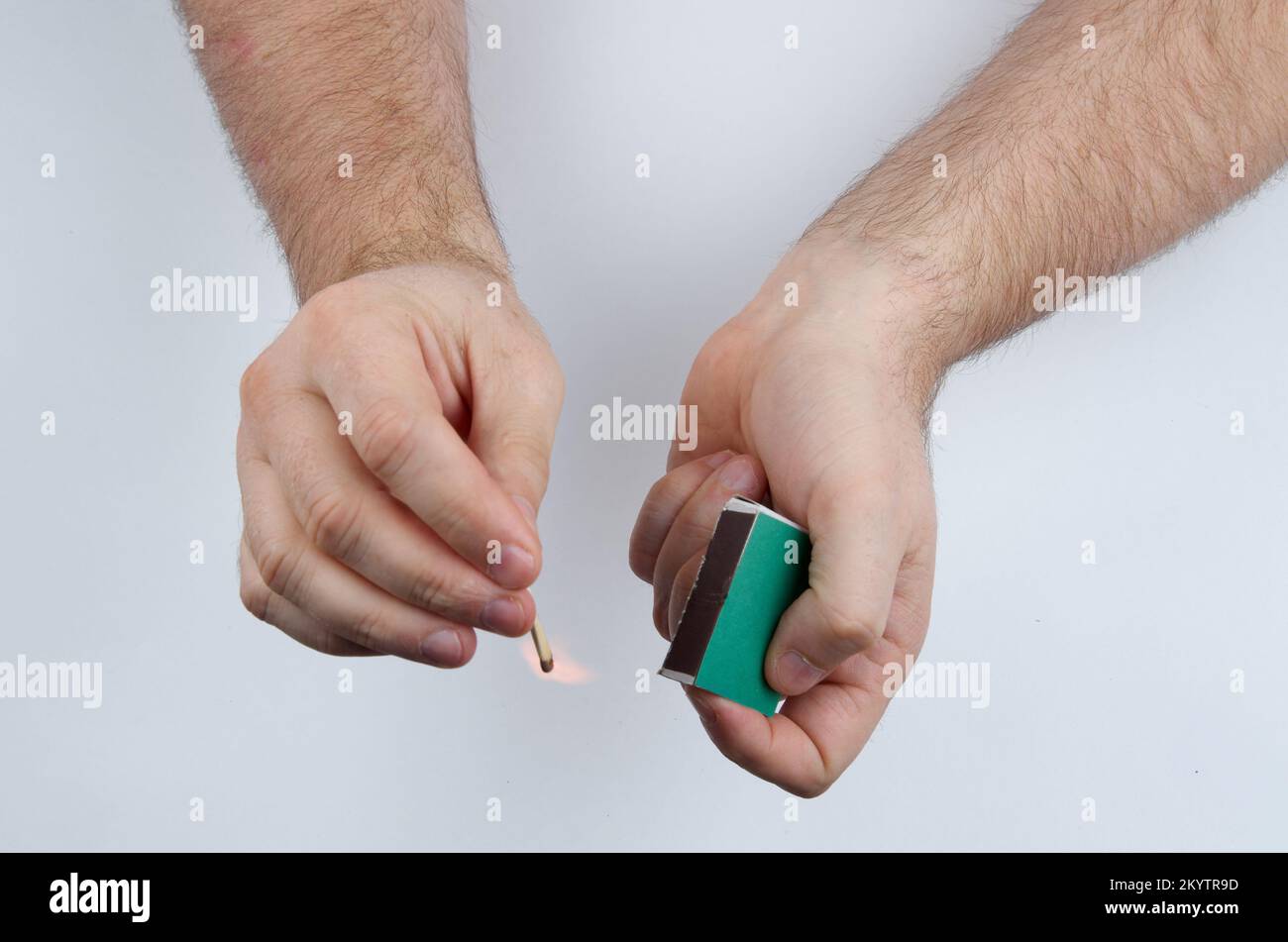 Lighting a match. Close-up of hands, matchbox and match on light-gray ...