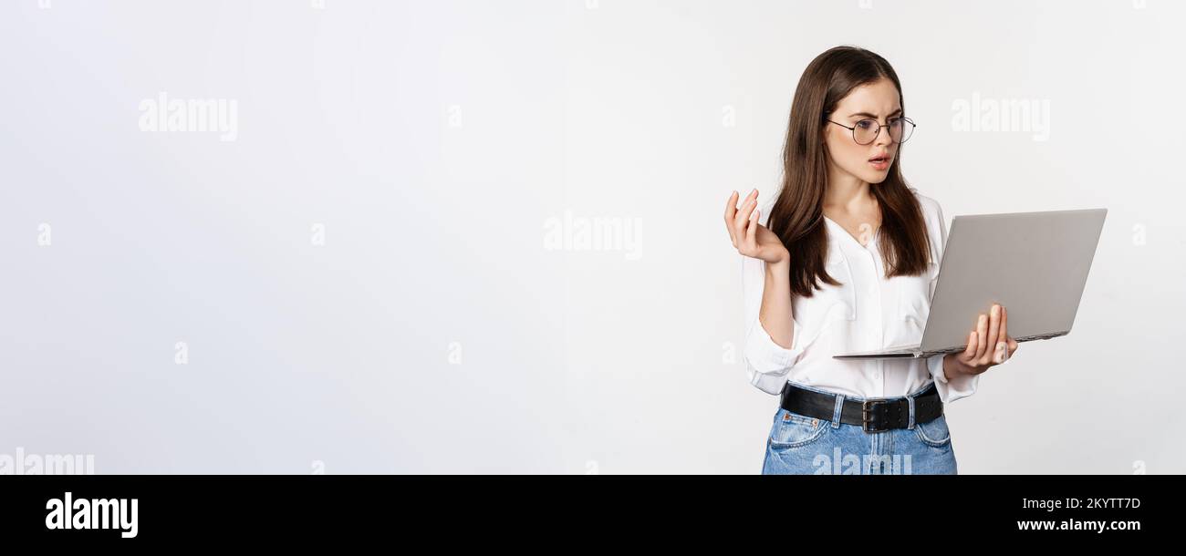 Shocked woman looking at laptop screen confused, stunned about smth on ...