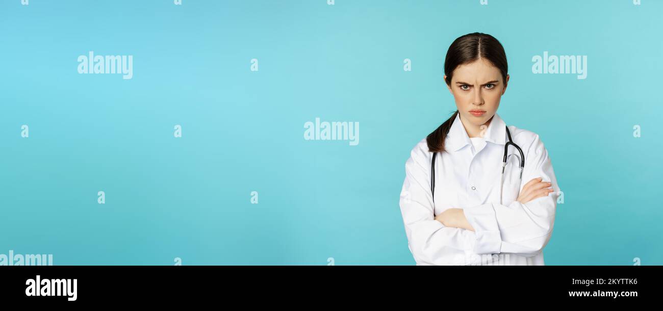 Angry doctor, female medical worker looking offended, cross arms on ...