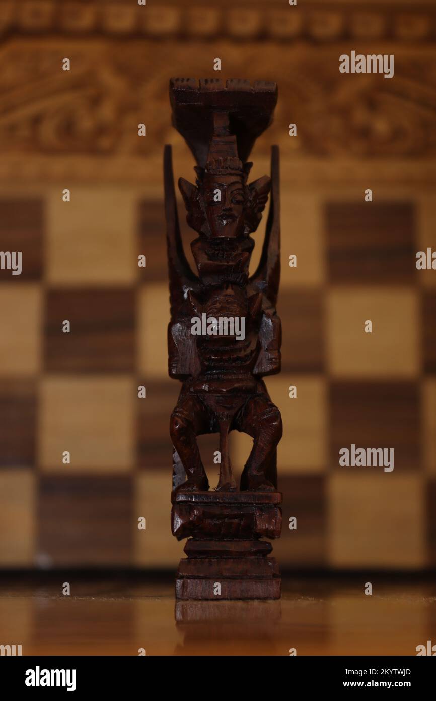 Mayan chess pieces photographed on a background showing a chess board ...