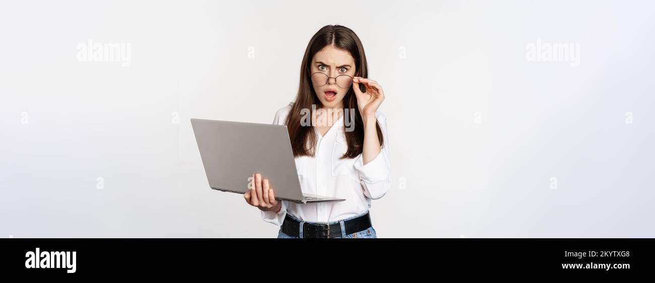 Shocked woman looking at laptop screen confused, stunned about smth on ...