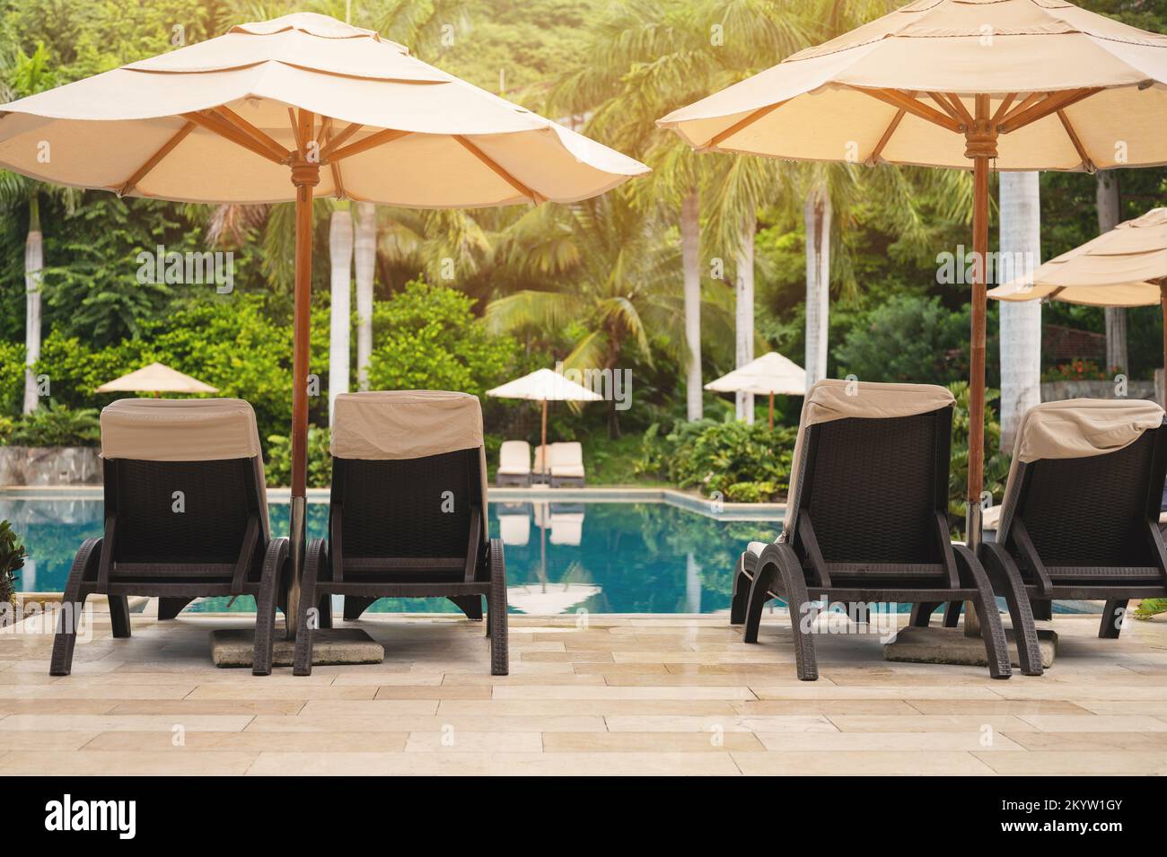 Chairs and umbrella next to pool in hotel resort on bright sunny day ...