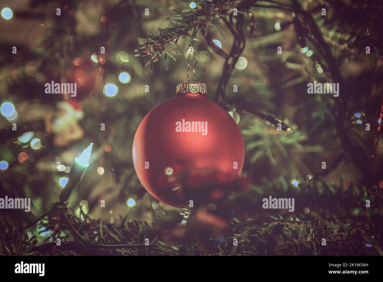 Holiday background with red ball in tree with lights Stock Photo - Alamy