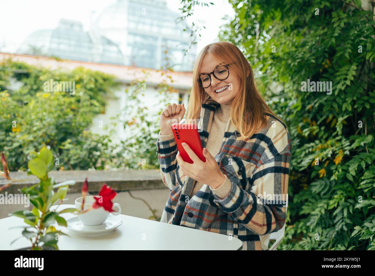 Charming woman with beautiful smile reading good news on mobile phone ...