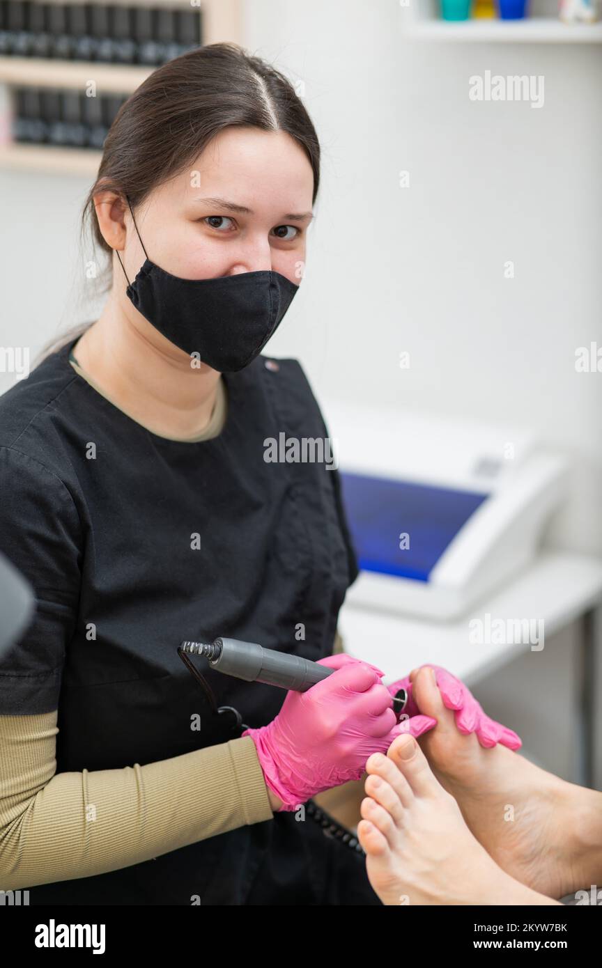 The pedicure master processes the client's foot using an apparatus with ...