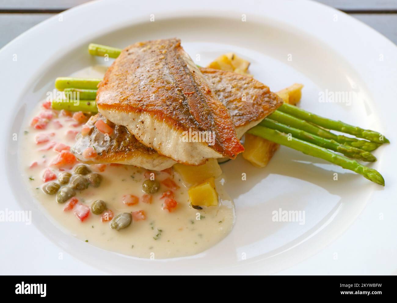 Plate of delectable pan seared sea bass with tomato caper mustard cream ...