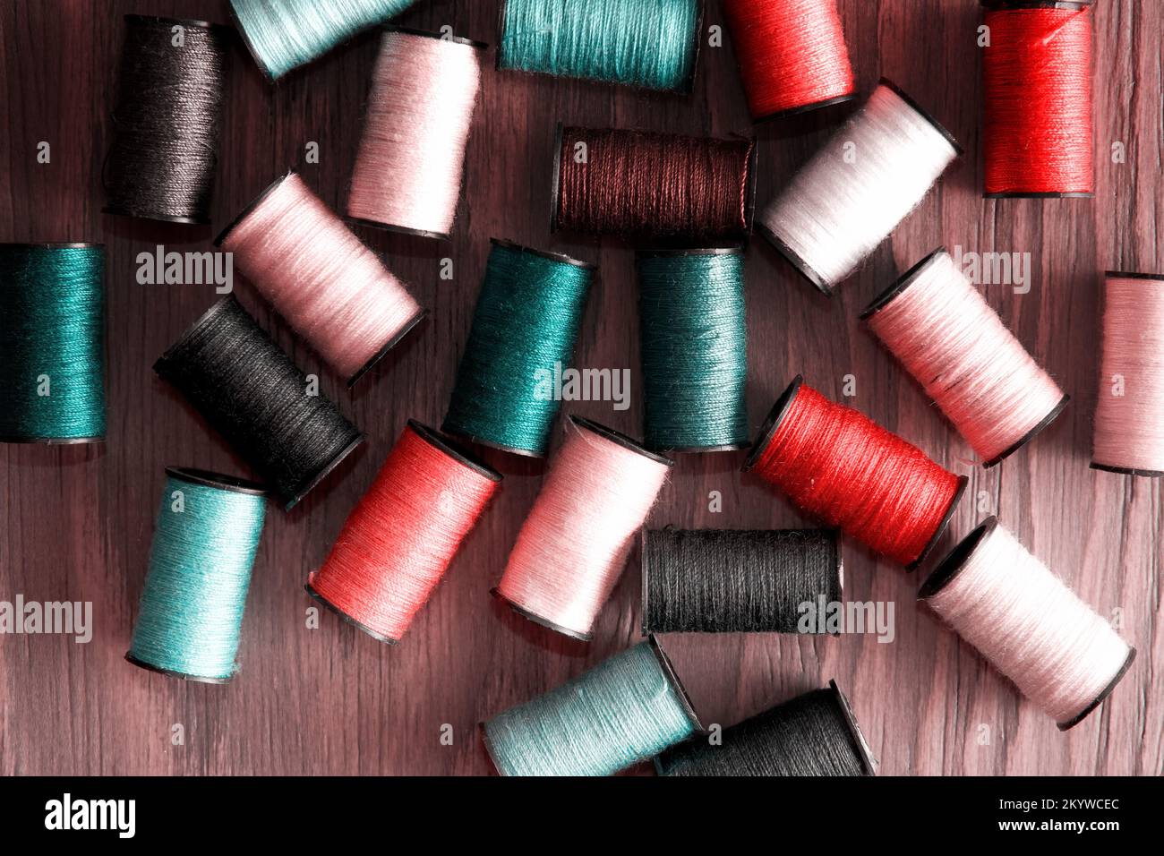 Pink and turquoise colored thread reels scattered on the tailor table ...