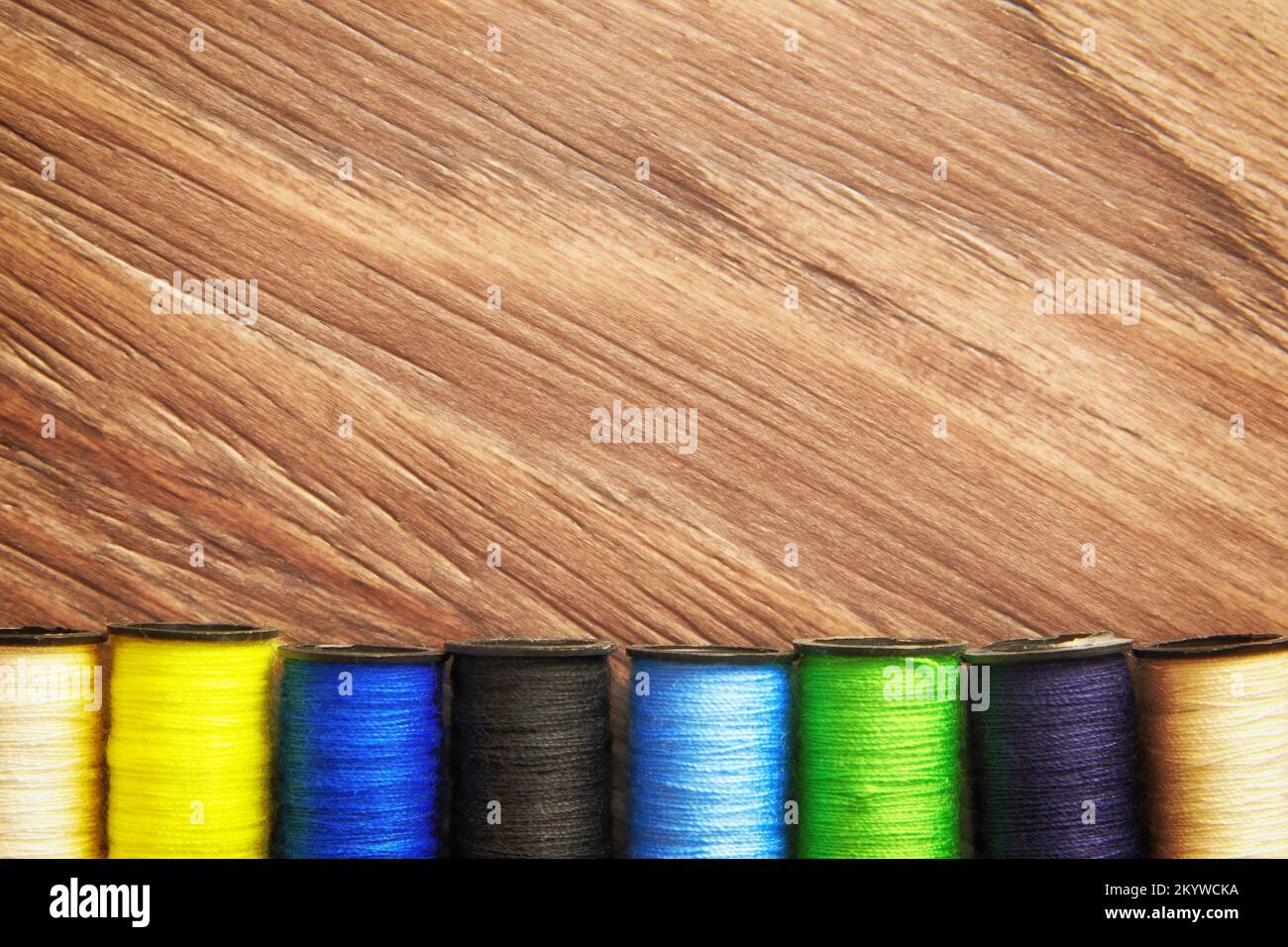 Pink and turquoise colored thread reels row on the tailor table ...