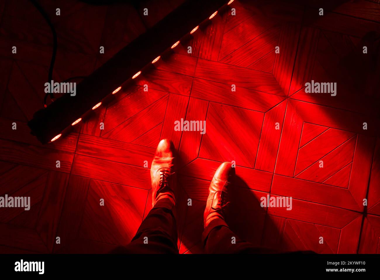 Red light lighting up feet in classic shoes on a wooden floor Stock ...