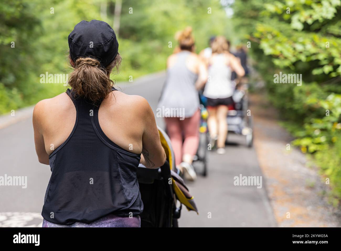 Backshot of mother walking with her baby in the stroller outside in a ...