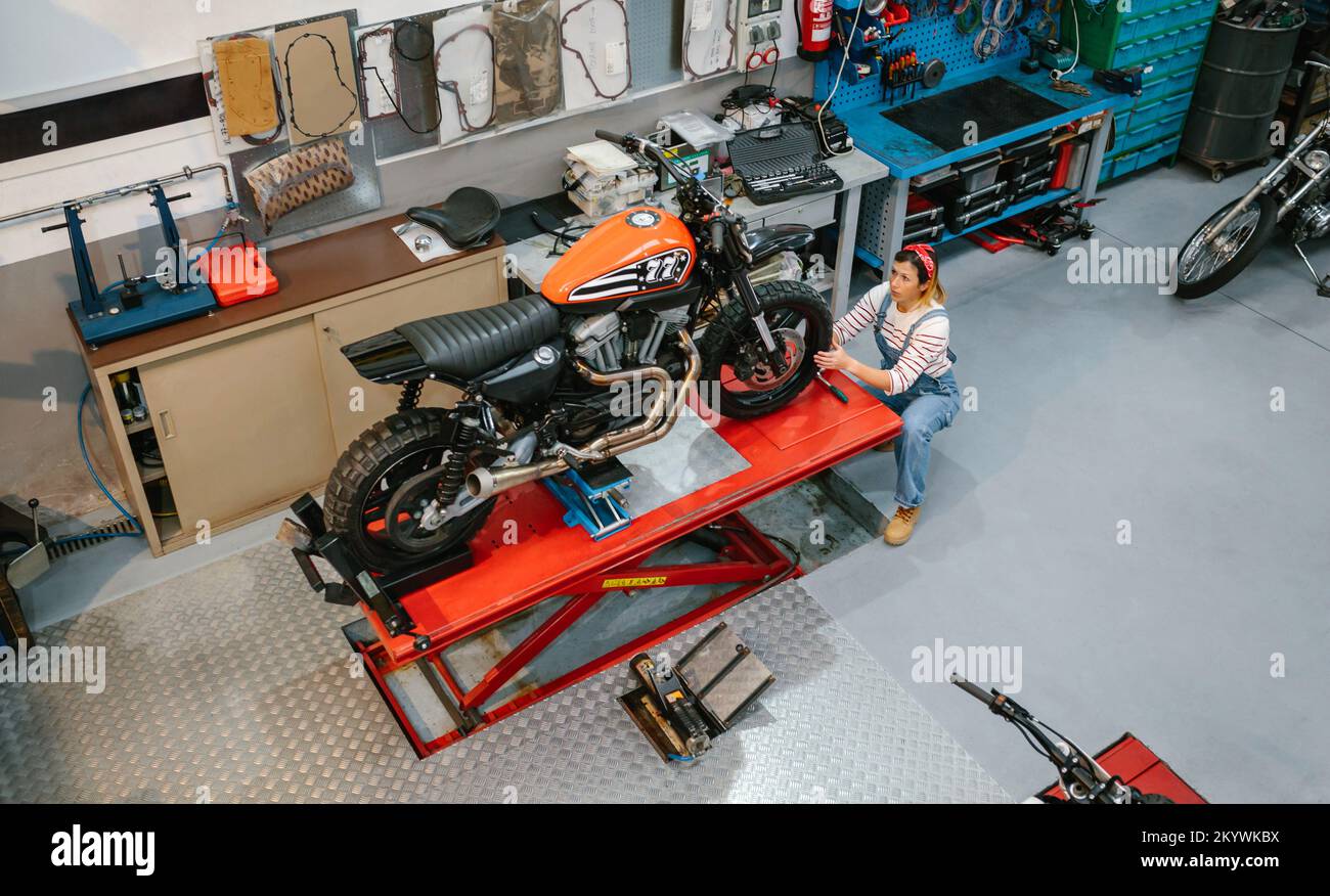 Mechanic woman reviewing custom motorcycle over platform Stock Photo ...