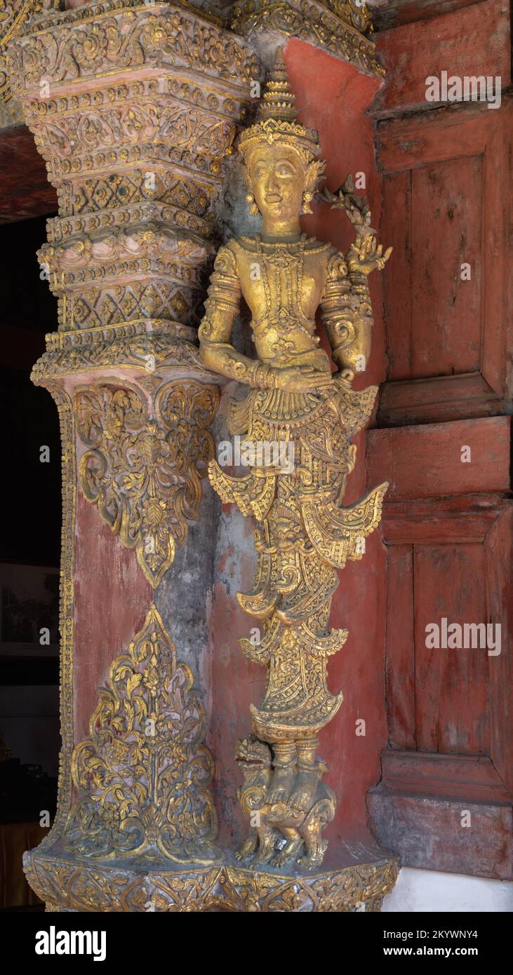 Gilded stucco sculpture of deity standing on lion at the entrance of ...