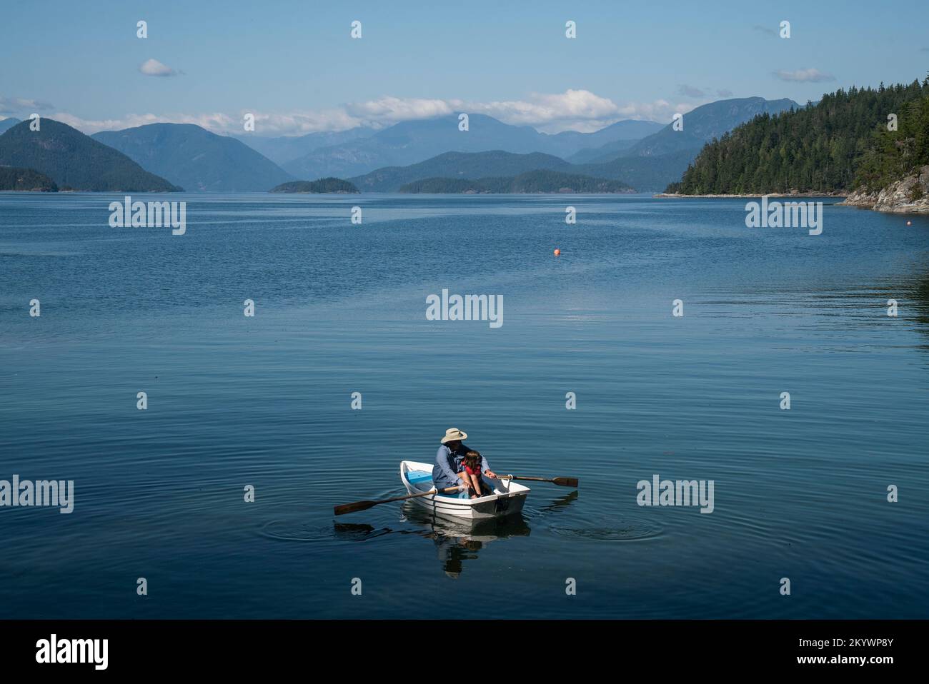 A grandfather and granddaughter in a small row boat in a large bay ...