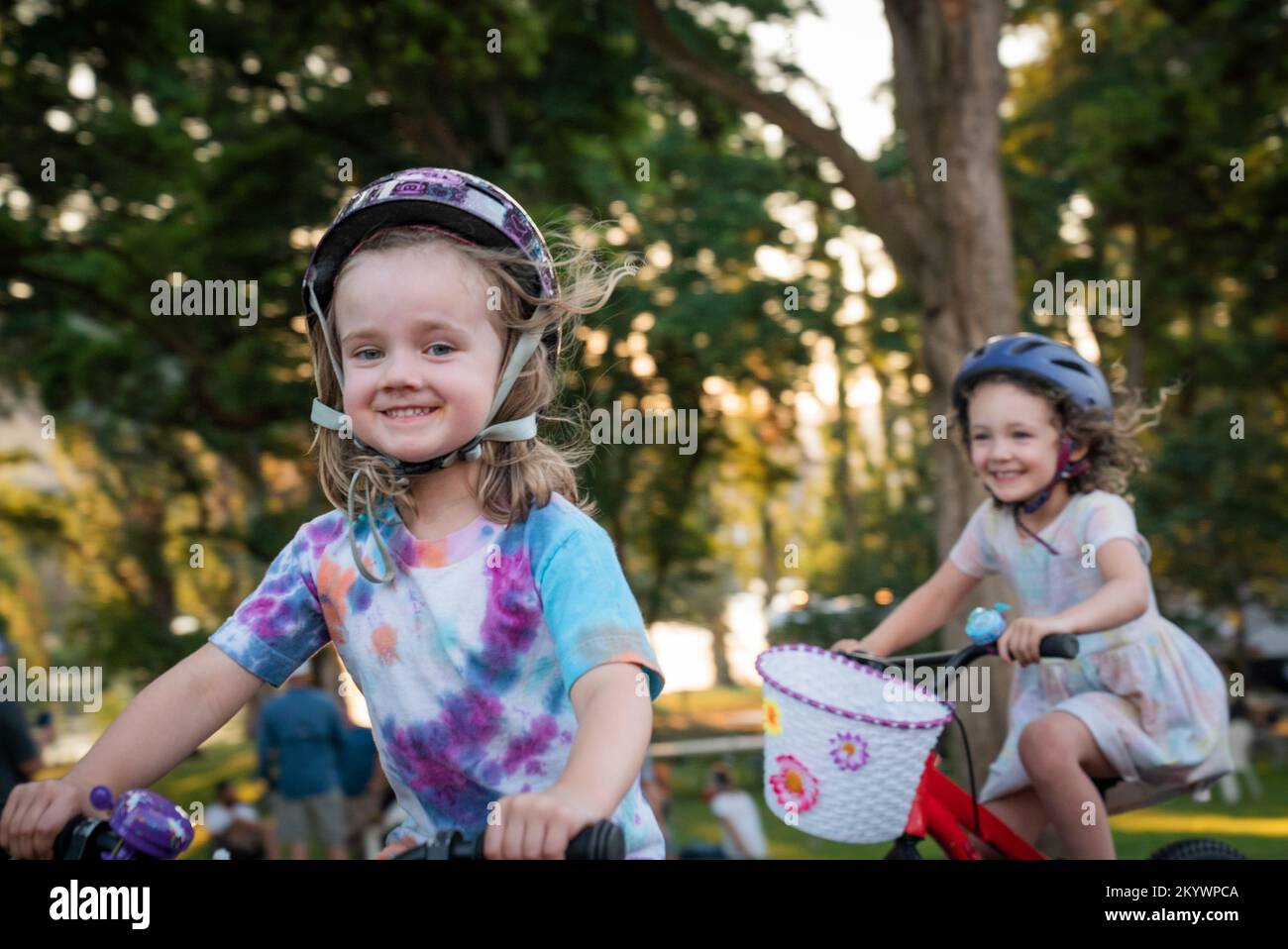 Two young girls ride bikes at sunset Stock Photo - Alamy