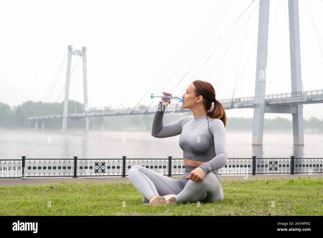 Woman sitting in yoga pose , drinking water in urban background Stock ...