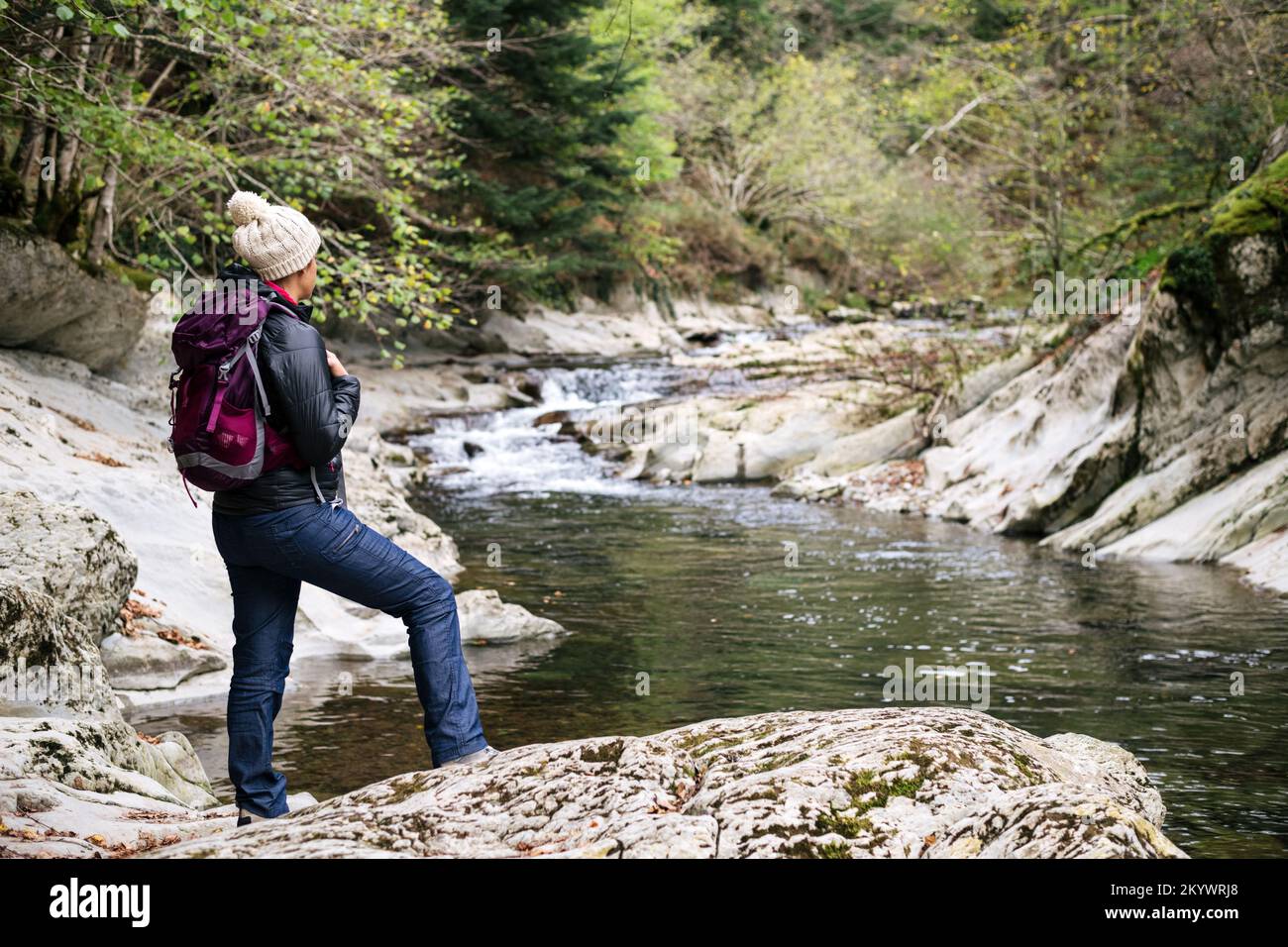 Woman with wool hat and backpack looking at the riverside landscape ...