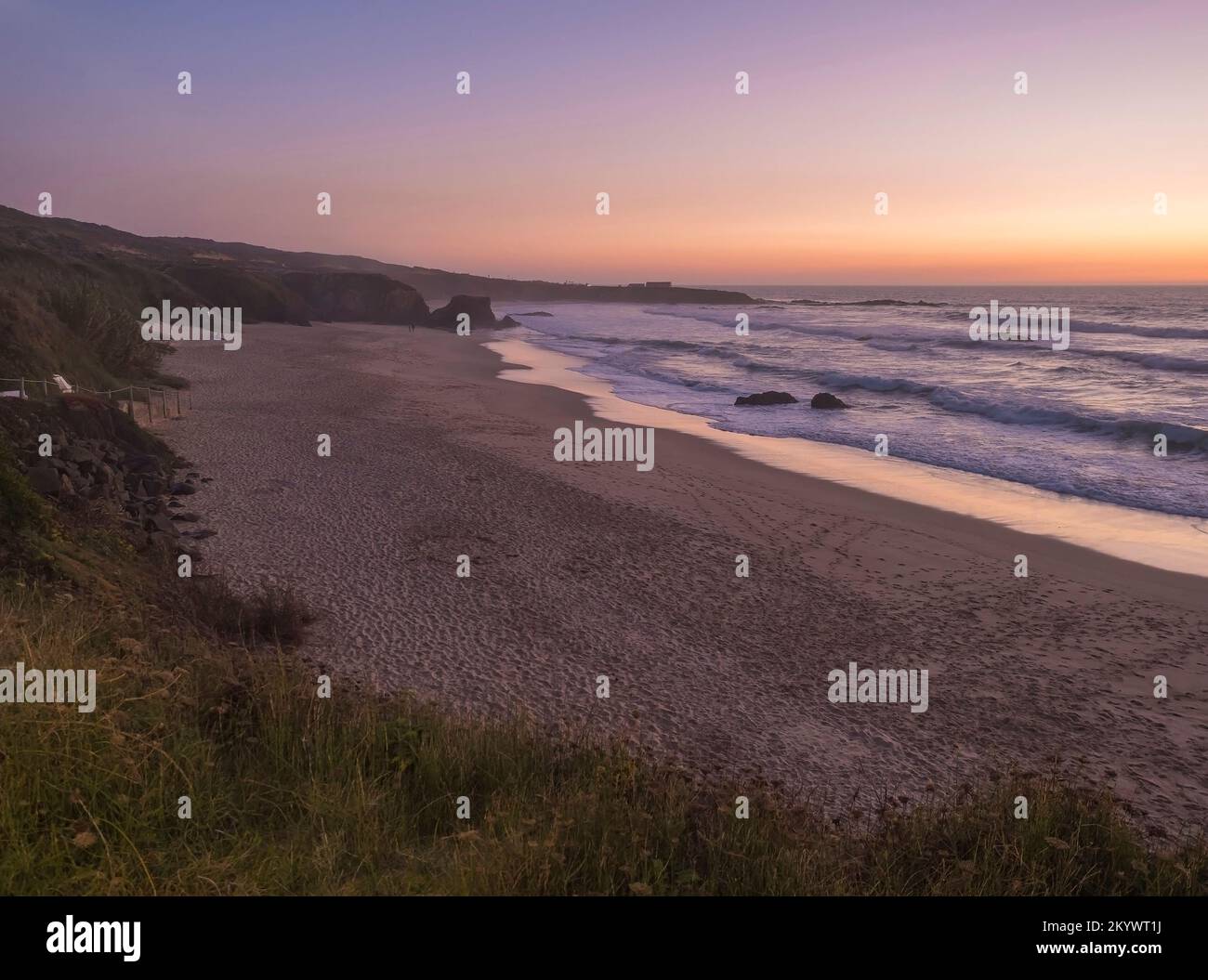Sunset view of sand beach Praia Grande de Almograve with ocean waves in ...