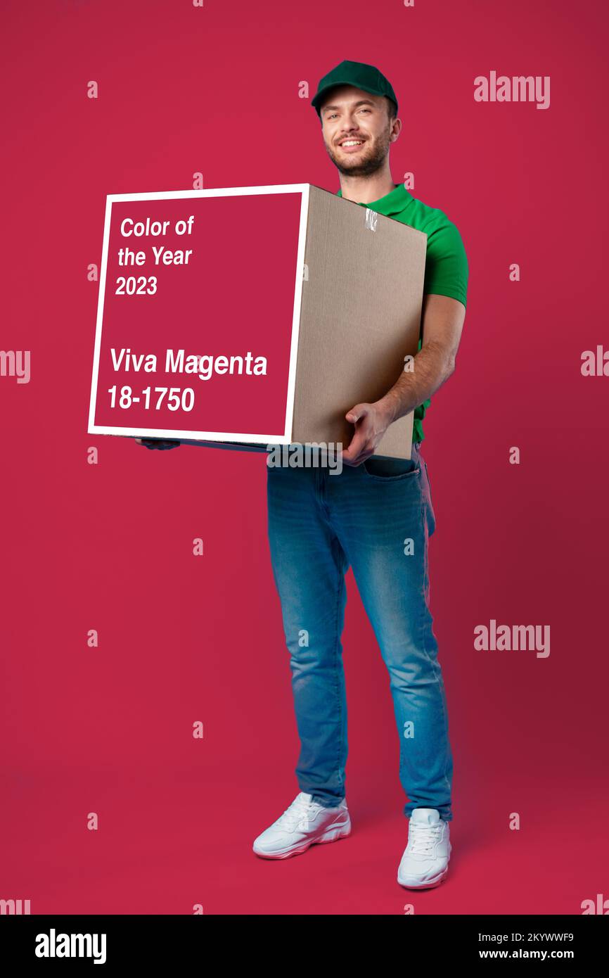 Delivery man with box in studio against magenta background. Color of ...