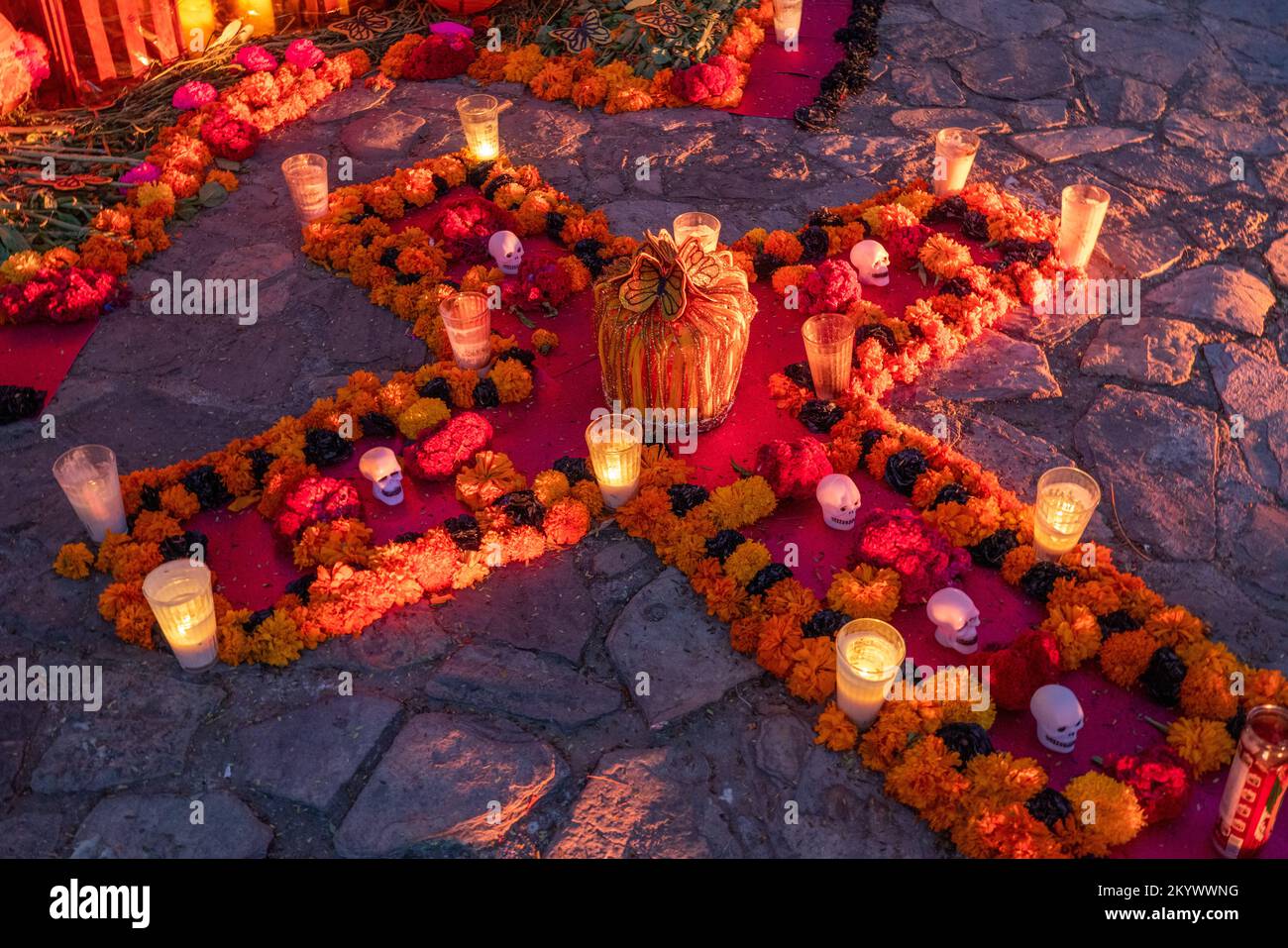 A floral cross in front of an ofrenda in a public square for Day of the ...