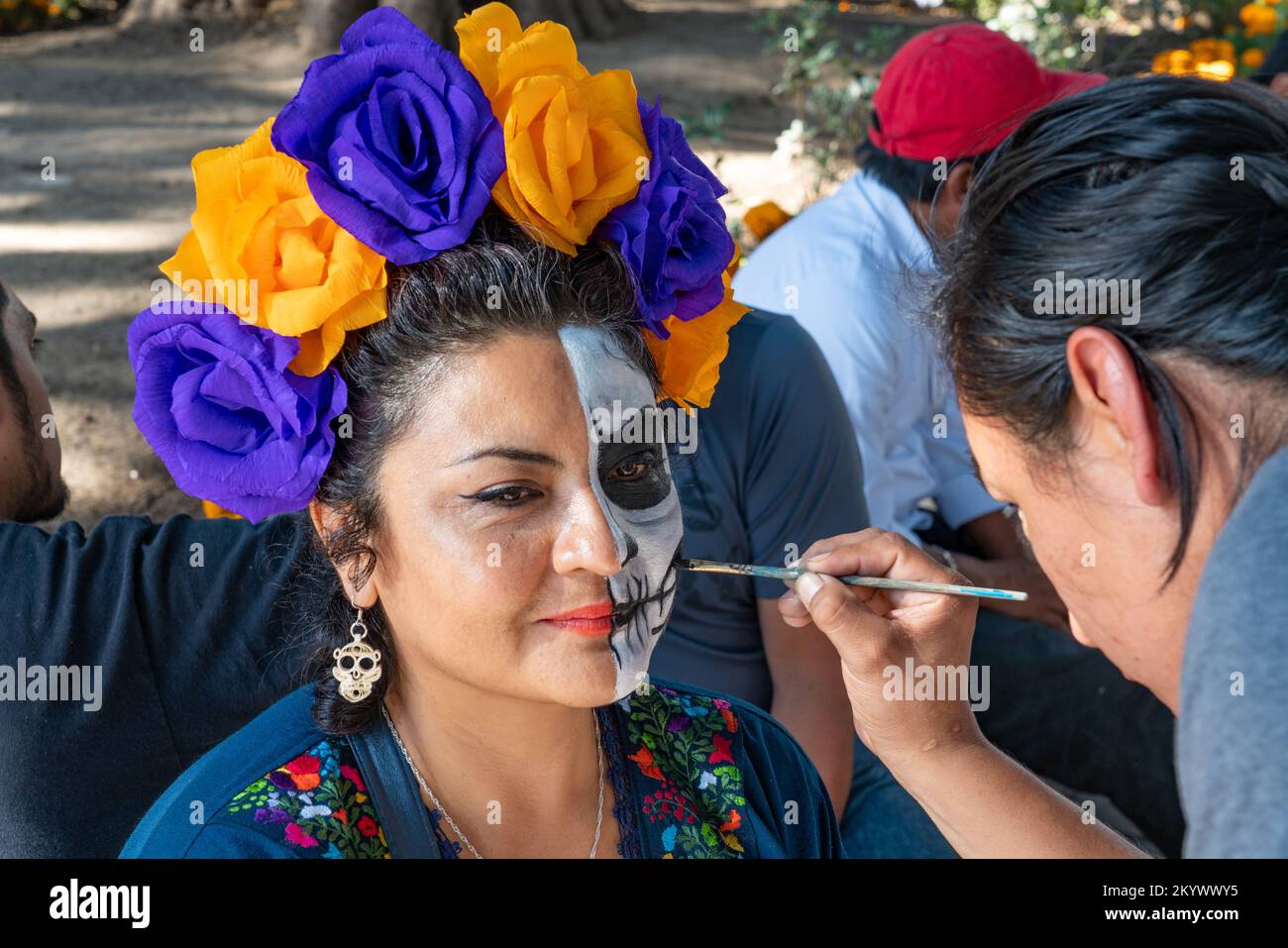 A woman getting her face painted for the Day of the Dead celebration in ...