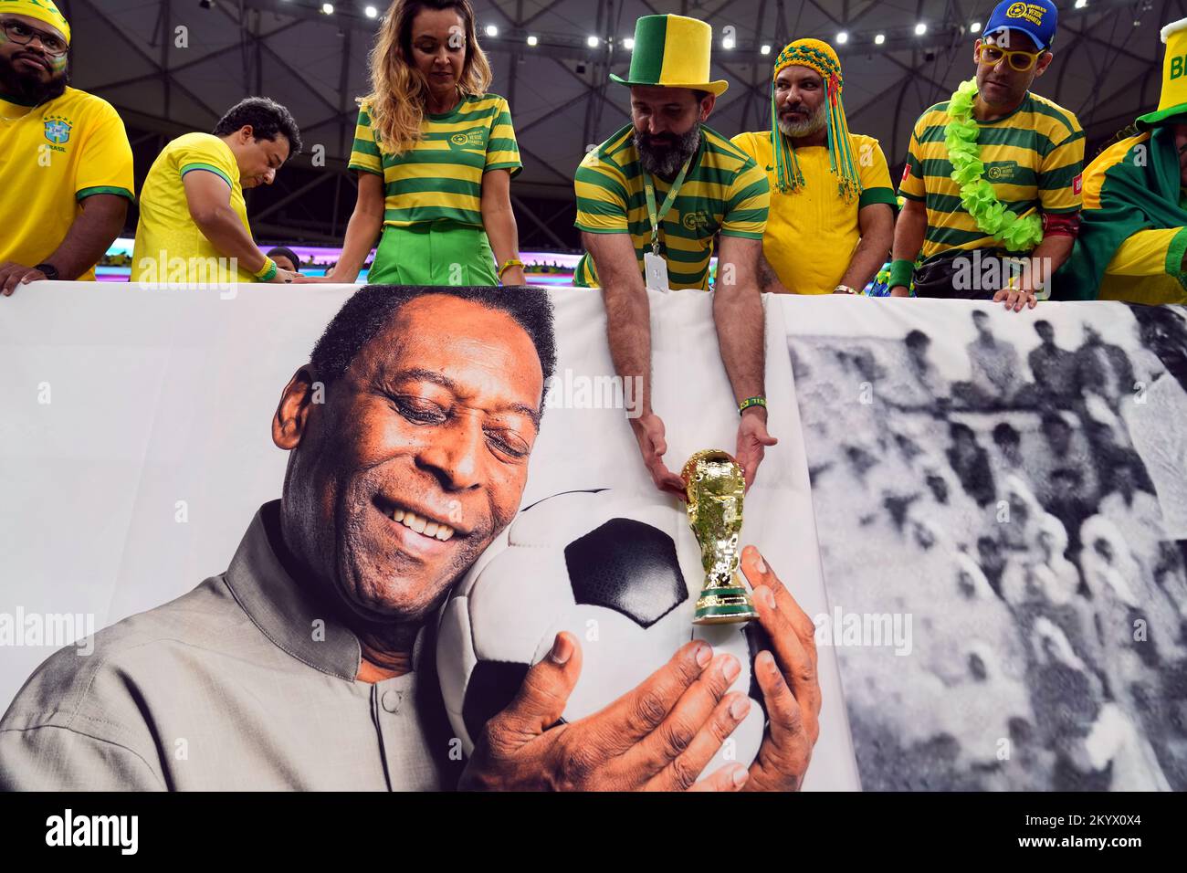 A Brazil fan holds a replica World Cup trophy over a picture of former ...