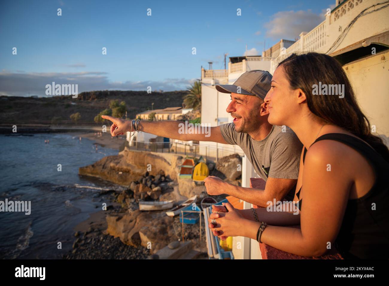 Two friends on holiday in Spain observe the sea during sunset, outdoor ...