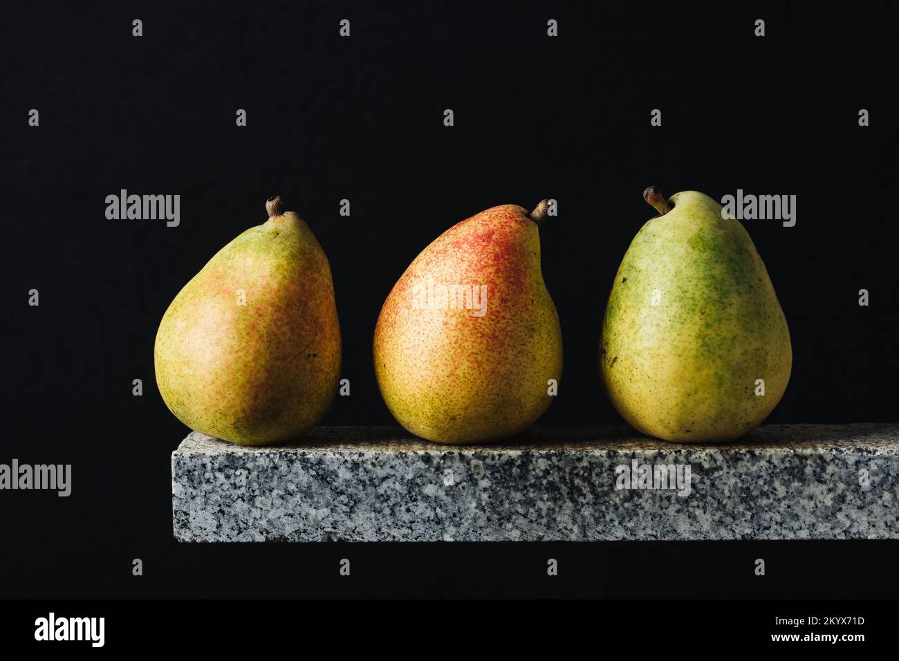 Three ripe yellow pears on a dark background Stock Photo - Alamy
