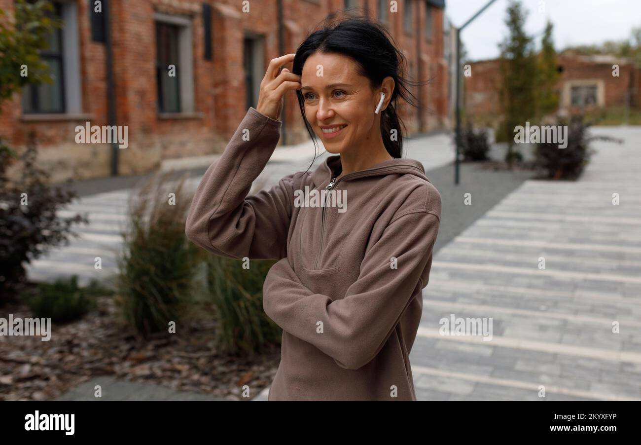 Portrait of a pretty athletic brunette in a brown hoodie and wireless ...
